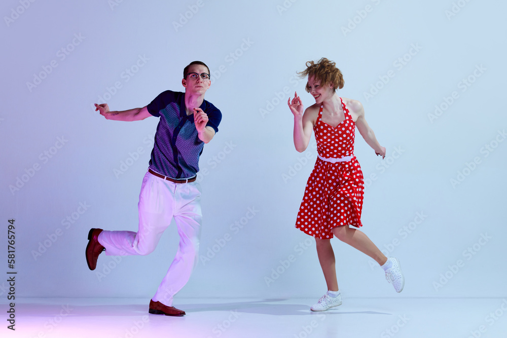 Beautiful young couple, man and woman in stylish costumes dancing retro ...