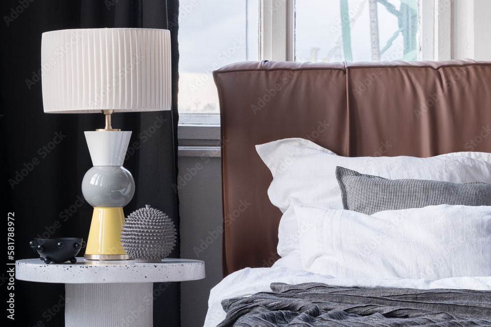 Elegant lamp on bedside table next to cozy bed Stock Photo | Adobe Stock