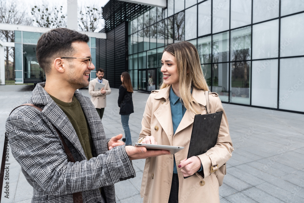 Young businesspeople standing in front of office building talking ...