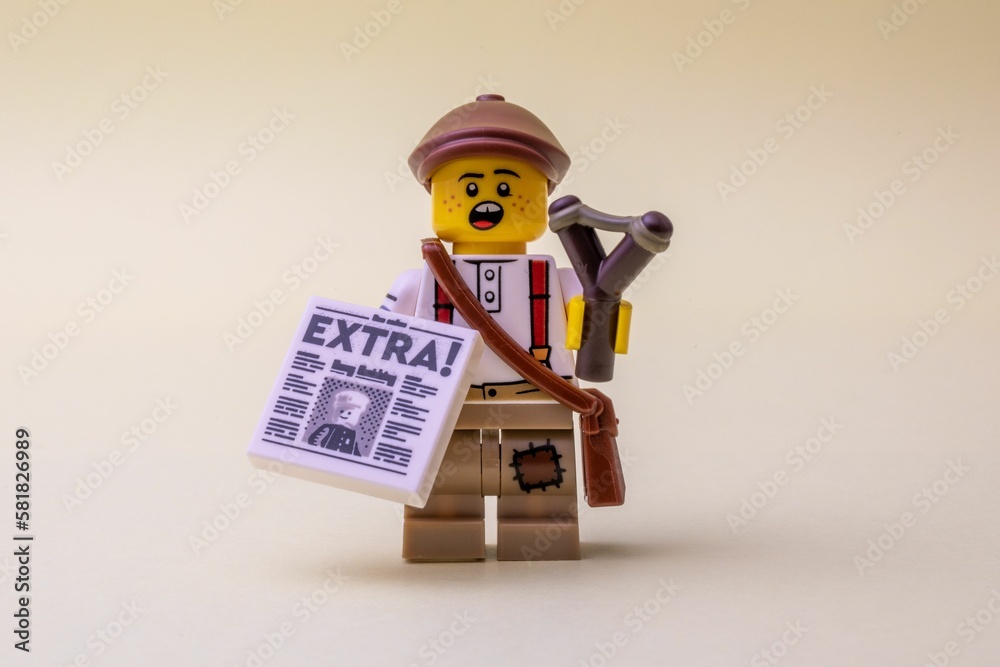 LEGO minifigure toy holding newspaper and slingshot on pastel ...