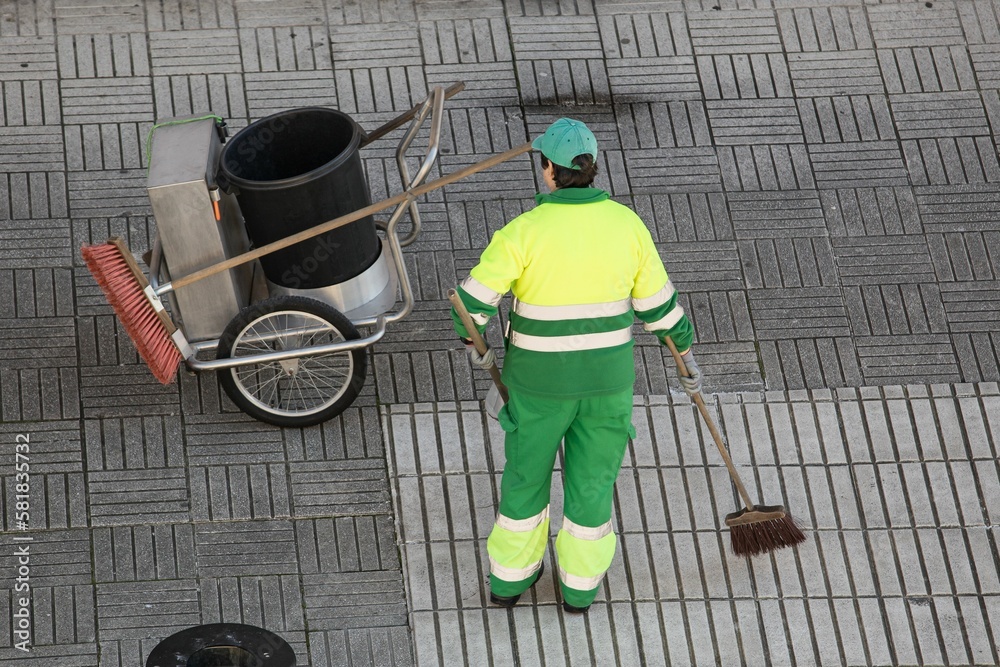 Street sweeper working on a sidewalk with her shovel, trolley and broom ...
