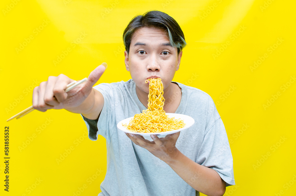 Happy euphoric asian young man in grey tshirt eating instant fried ...