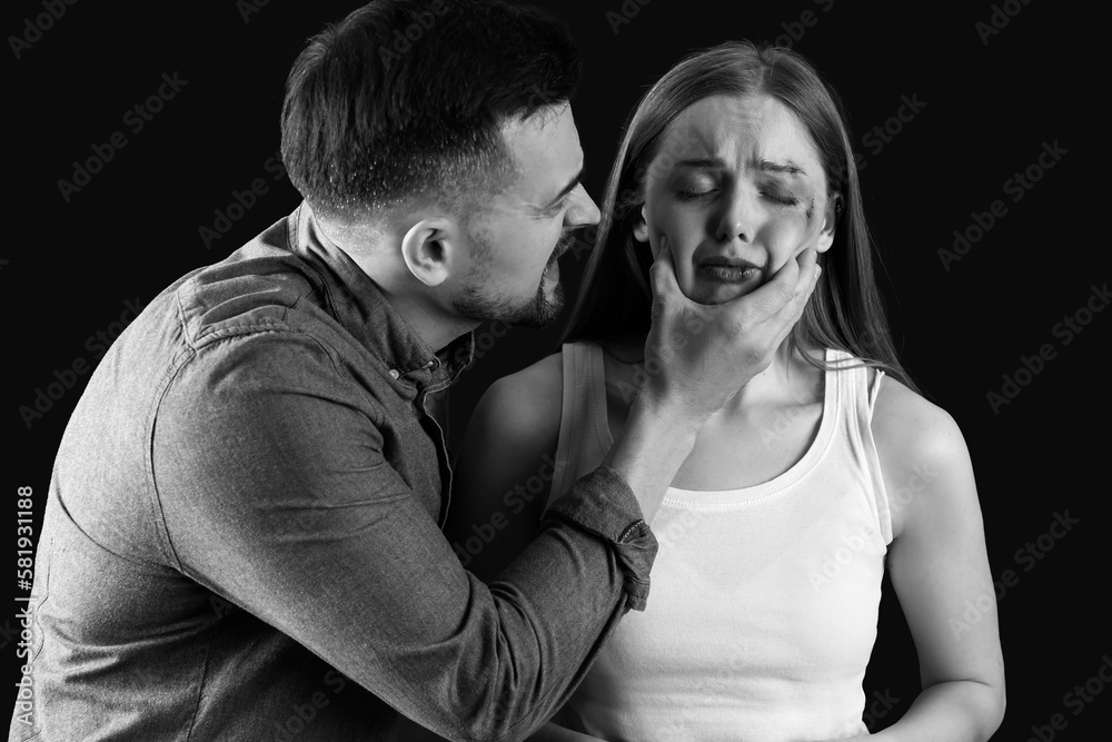 Bruised young woman with her angry husband on dark background. Domestic ...