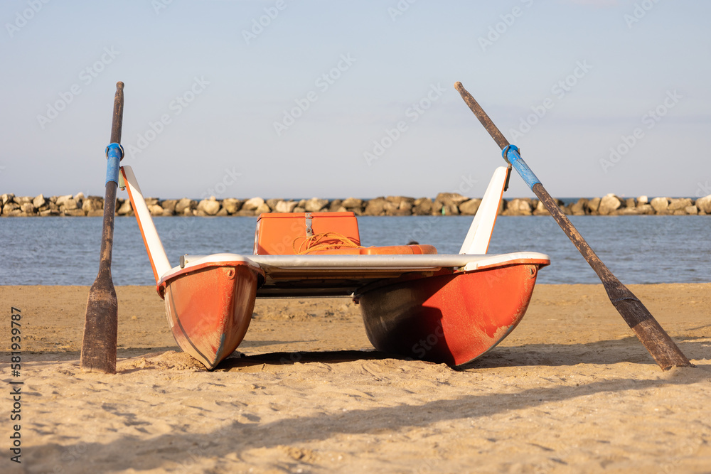 Classic italian rescue boat flanked by oars or rescue rowing catamaran ...