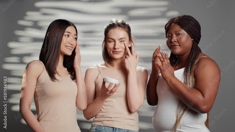 Group of beautiful girls applying moisturizing cream on camera ...