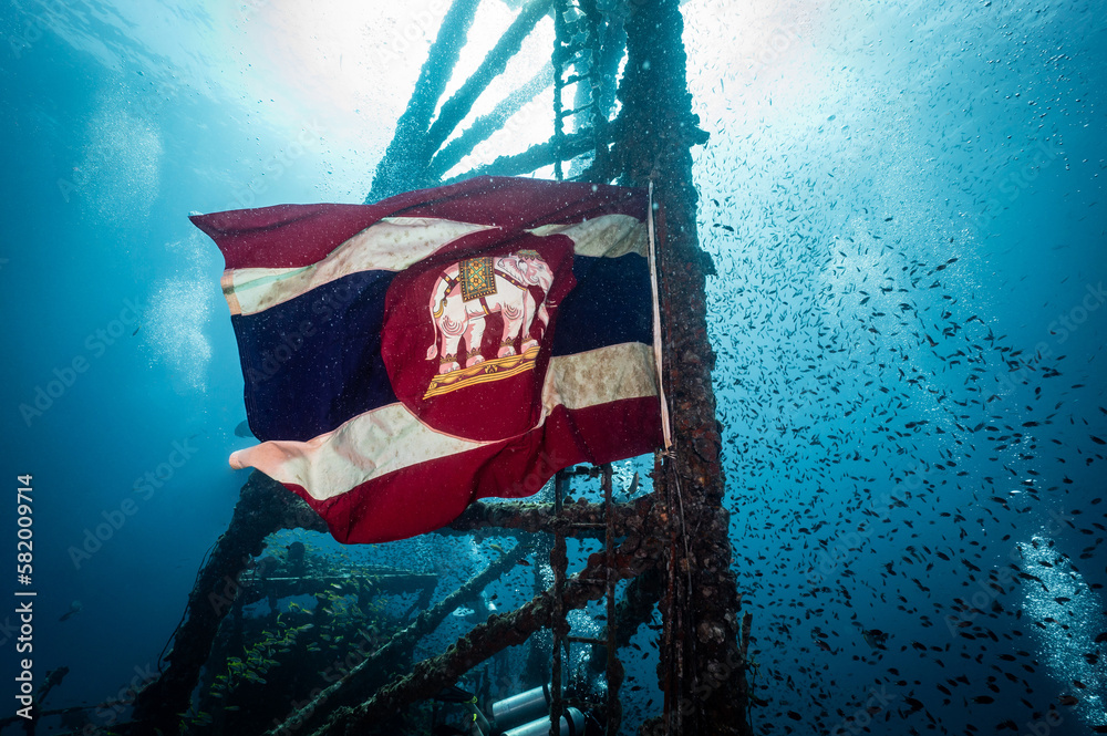 Thailand Naval Ensign Flag on HTMS Chang wreck ship with school of fish ...