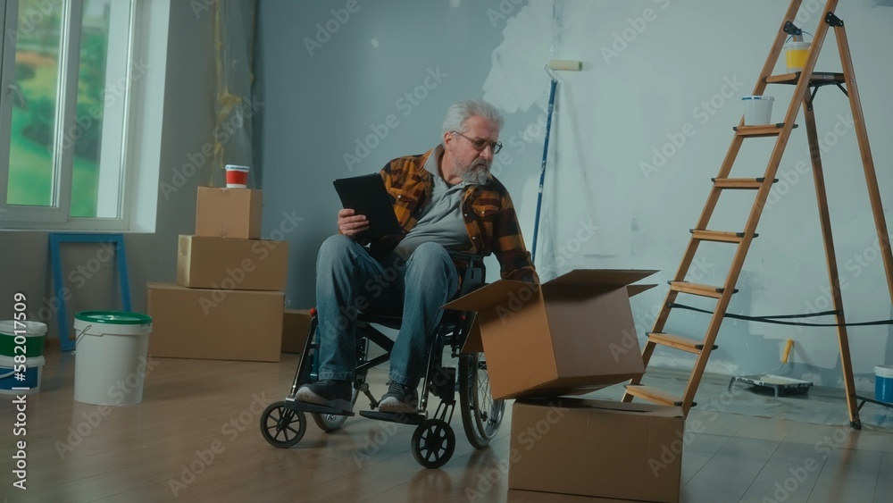 An elderly disabled man moves in a wheelchair plans renovation using a ...
