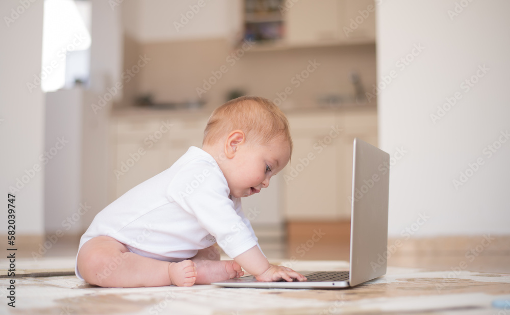 Child sit on floor. Baby is playing on laptop. Modern children and new ...