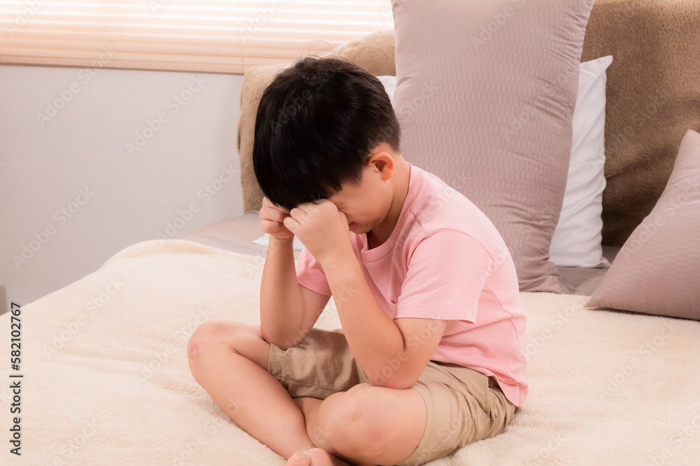 Asian adorable boy crying on bed because he didn't go out to play with ...