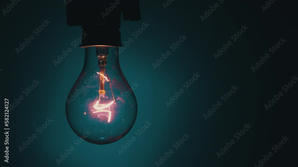 Light bulb flashes on a blue background in the dark. Slow turning on ...