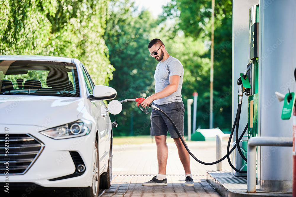 Confident man refueling his luxury auto. Driver with gasoline pump ...