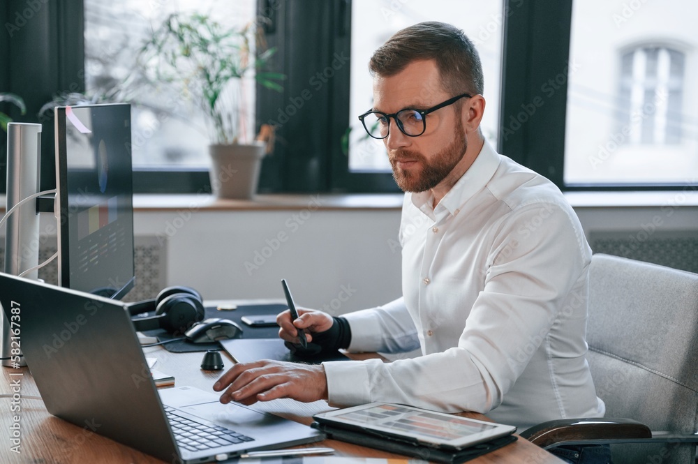 Side view. Man in formal clothes is working in the modern office. Using ...