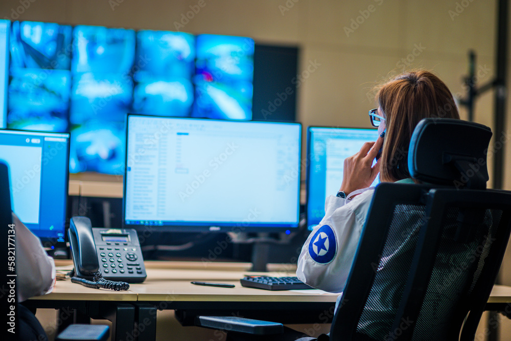 Female security guard sitting and monitoring modern CCTV cameras in a ...