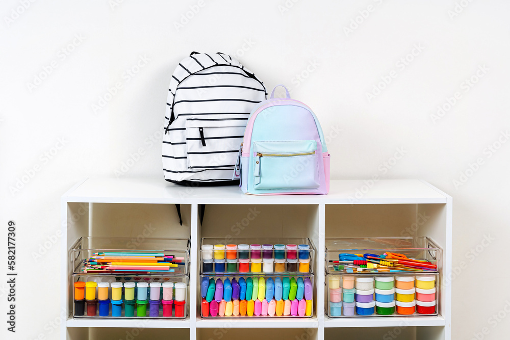 White shelving with kids backpack and various material for creativity ...