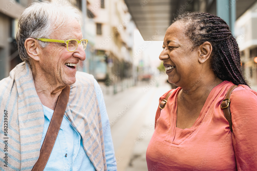 Happy multiracial senior friends talking while waiting at the bus ...