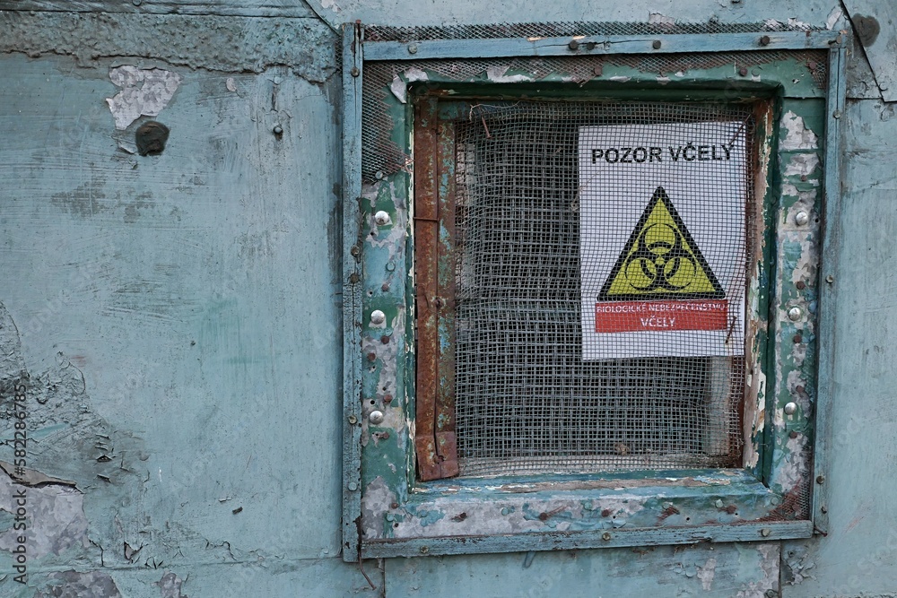 Window on garden shed with dense grating and warning sign of biological ...