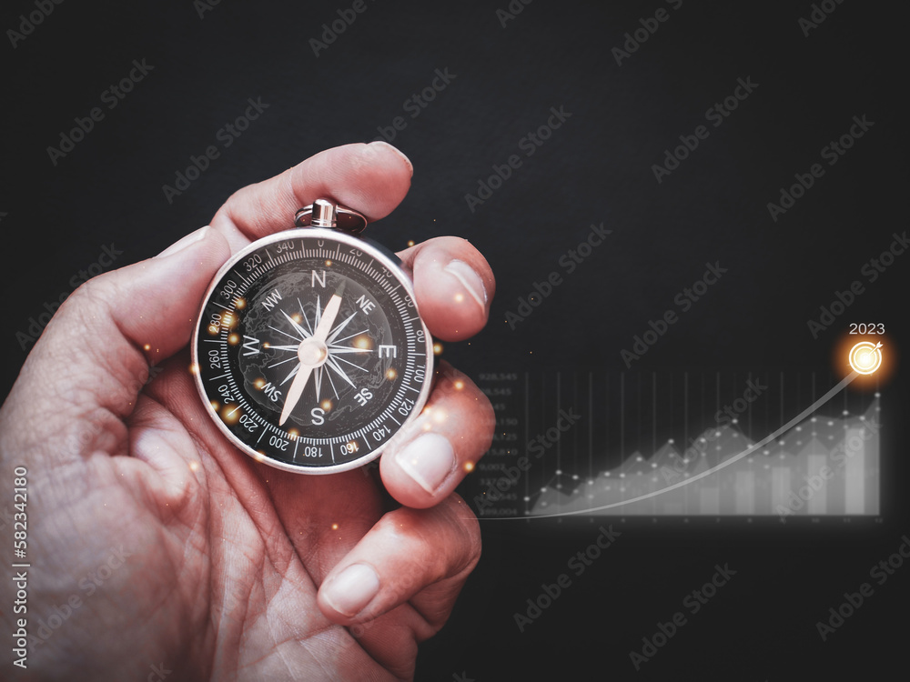 Businessman holding compass inside with globe icon and a graph showing ...