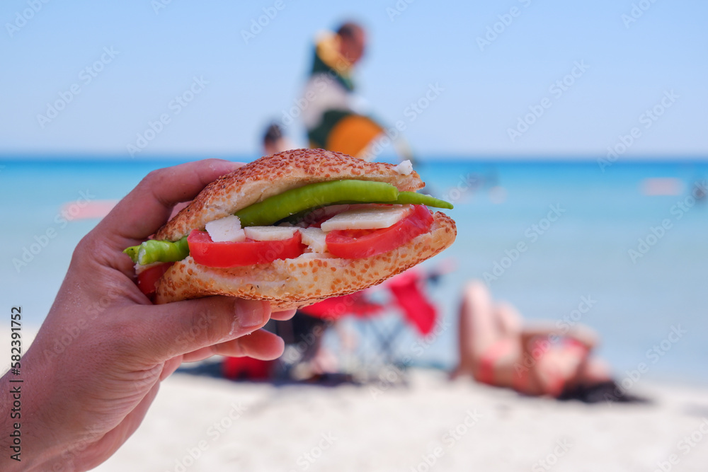 The hand of a man holding a sandwich prepared with the local bread of ...