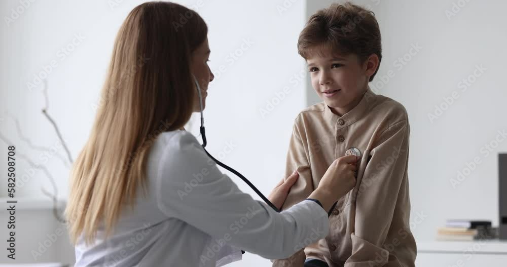Caring pediatrician woman examining little patient boy, applying ...