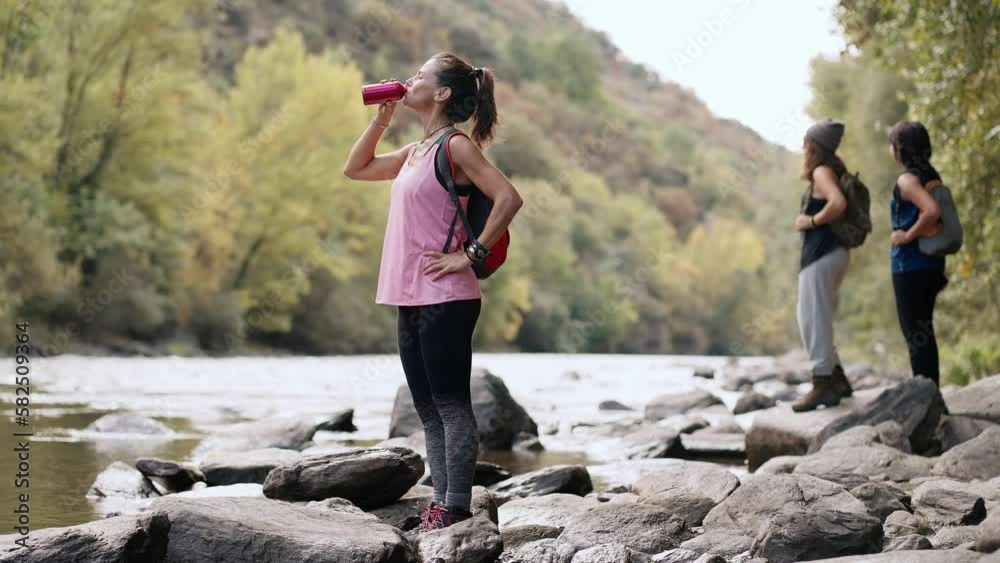 Video of woman trekker drinking water from canteen in a river in the ...
