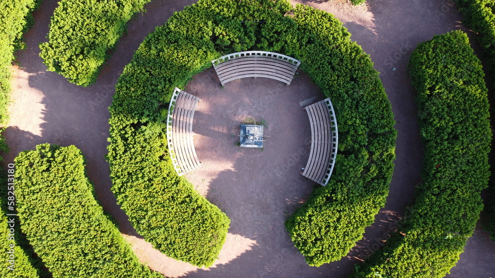 An aerial view of concentric ornate bushes with benches in the center ...