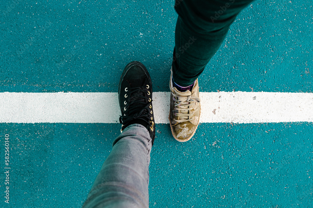 Two people foot standing on a white line on the ground. Border crossing ...