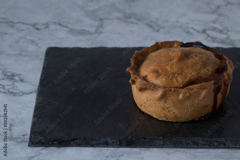 An empanada, a typical Mallorcan pastry, on a slate tile and a marble ...