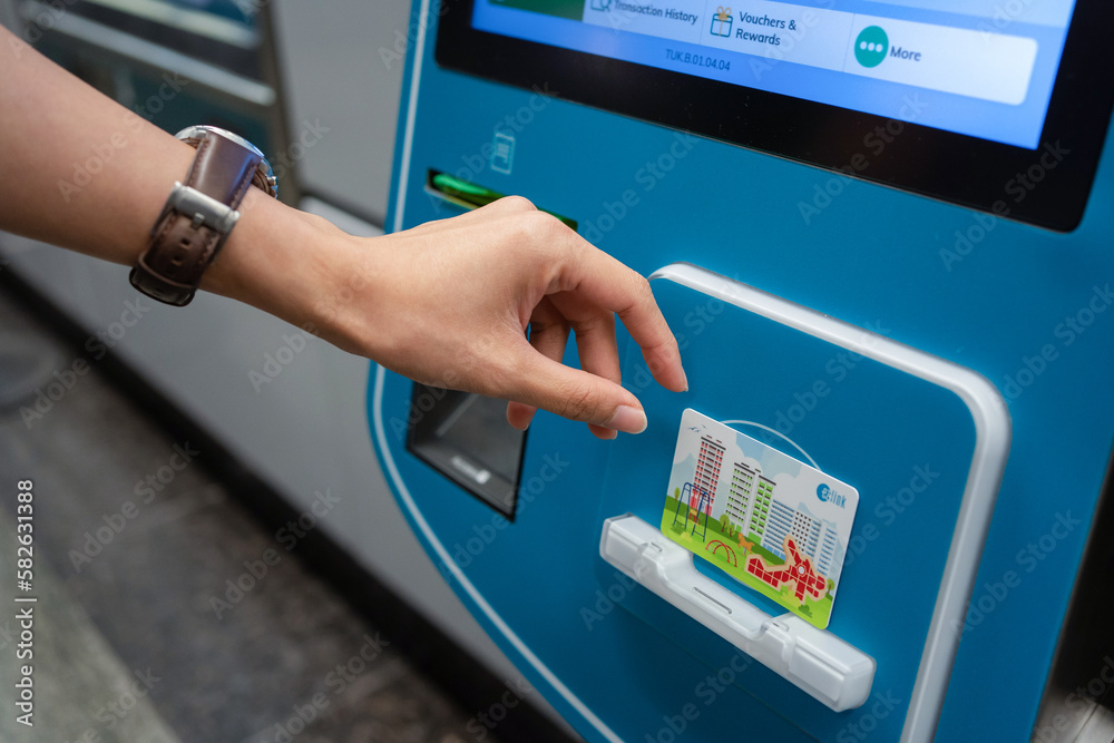 SINGAPORE - APR 19, 2022: Lady's hand placing the Singapore MRT Card ...