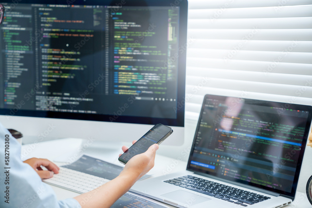 programmer writing program code with two monitors and working on a new ...