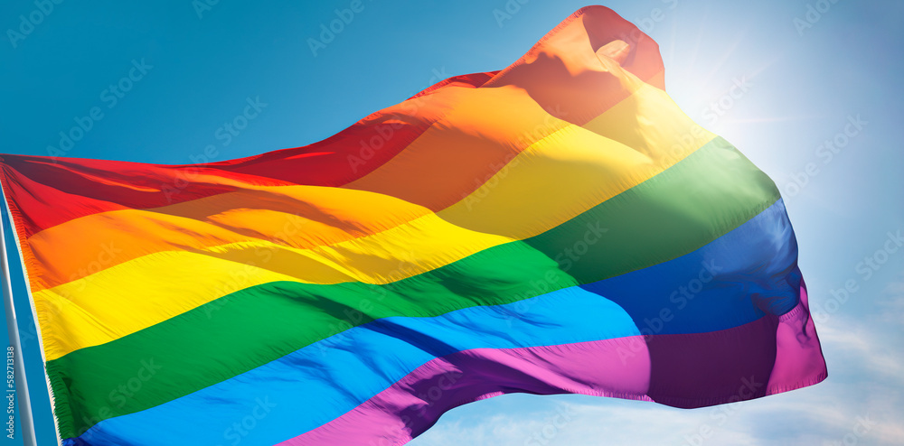 Vibrant and colorful LGBT flag waving in the sunny blue sky, symbol of ...