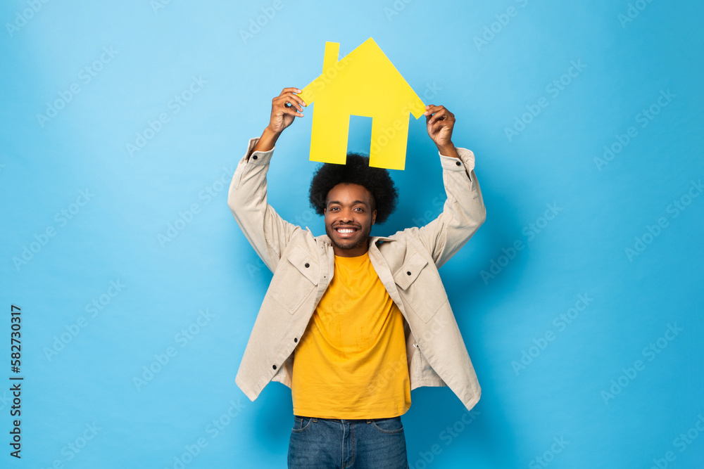Happy smiling Afro African-American man holding house cut out in ...