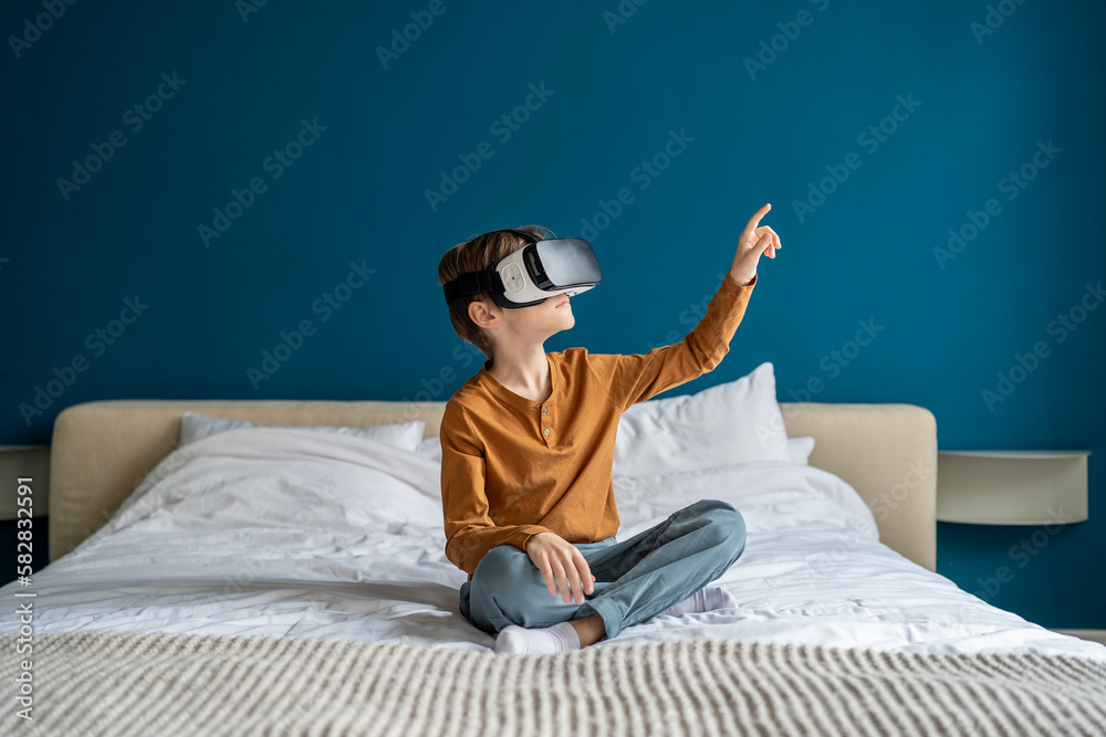 Child boy wearing virtual reality headset interacting with digital ...