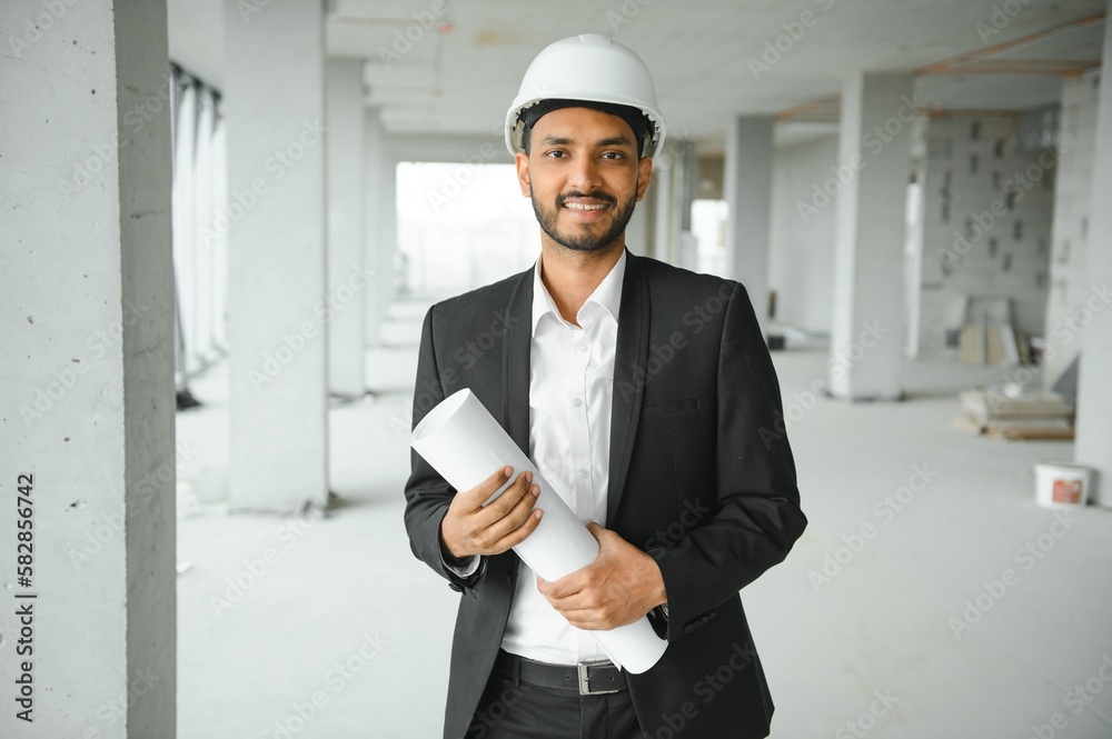 Indian construction site manager standing wearing helmet, thinking at ...
