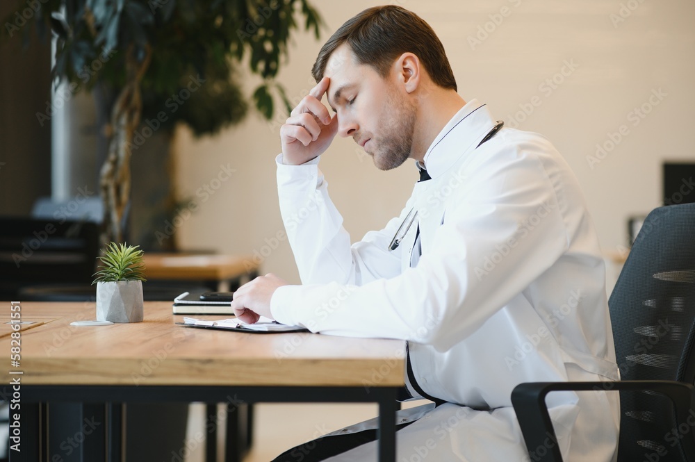 Stressed male doctor. Mid adult male doctor working long hours ...