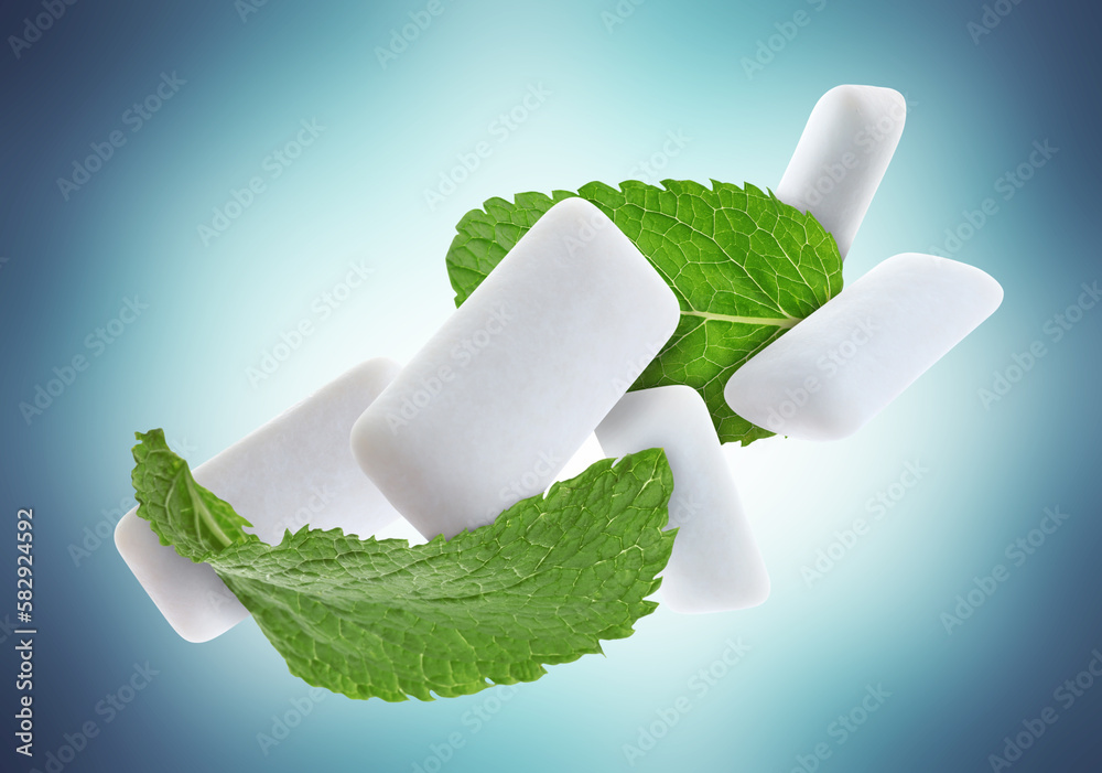 Fresh mint leaves and chewing gum pads falling on light blue background ...