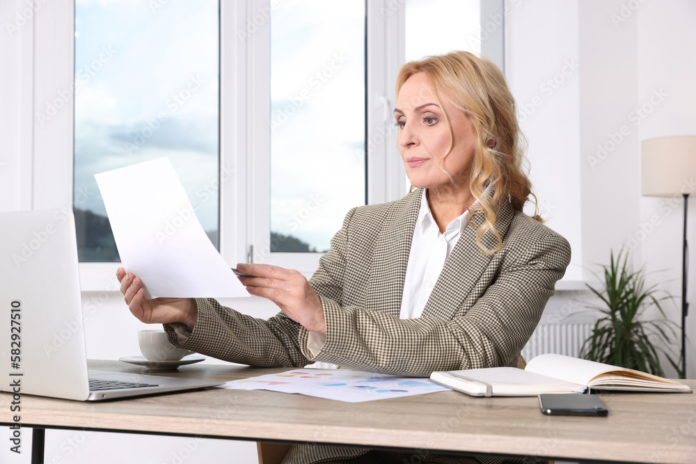 Lady boss with papers working near laptop at desk in office. Successful ...