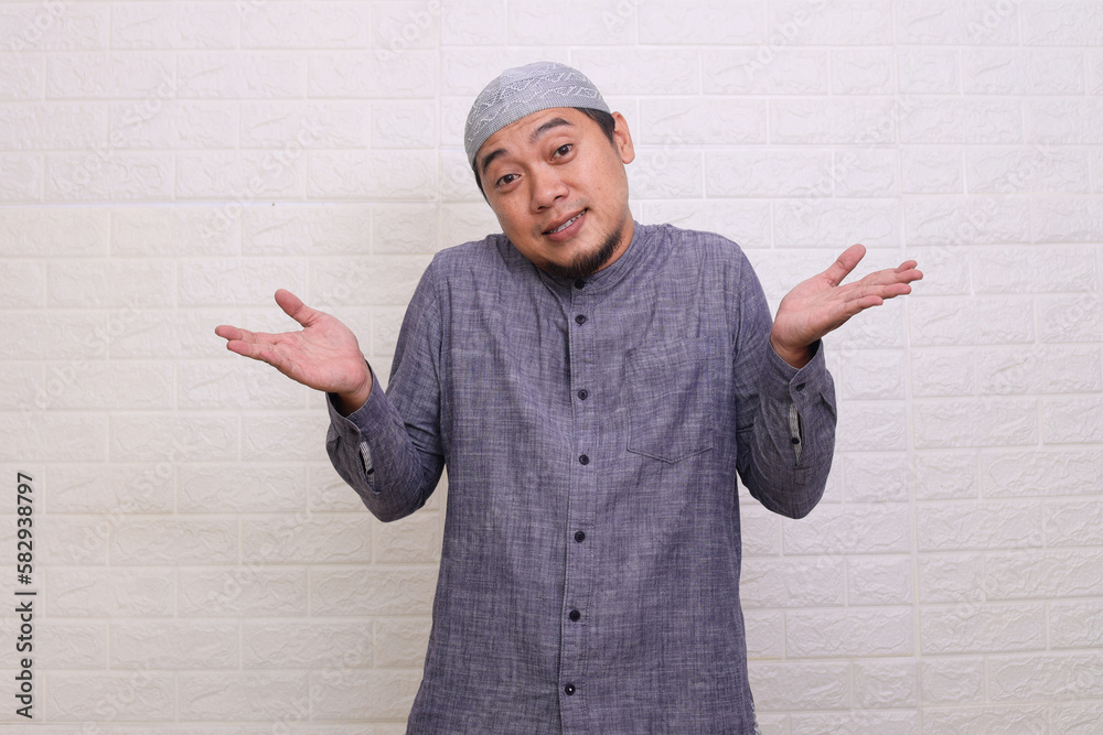 Confused Asian muslim man shrugging shoulders isolated on white ...