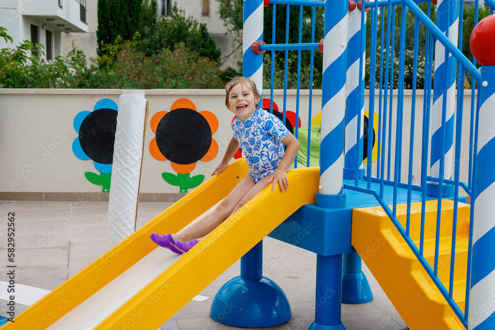 Foto de Little preschool girl sliding on a children slide in outdoor ...