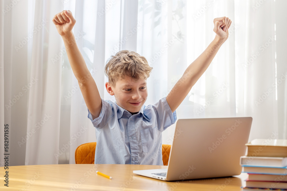 Excited schoolboy learning online on laptop Stock Photo | Adobe Stock