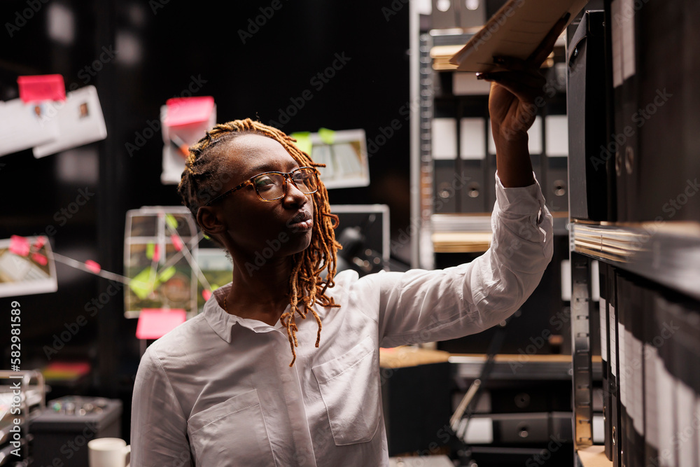 Private detective standing near folder rack and searching information ...