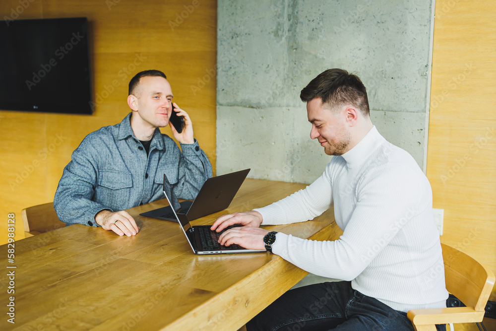 Two confident young people are sitting together at a table and one of ...