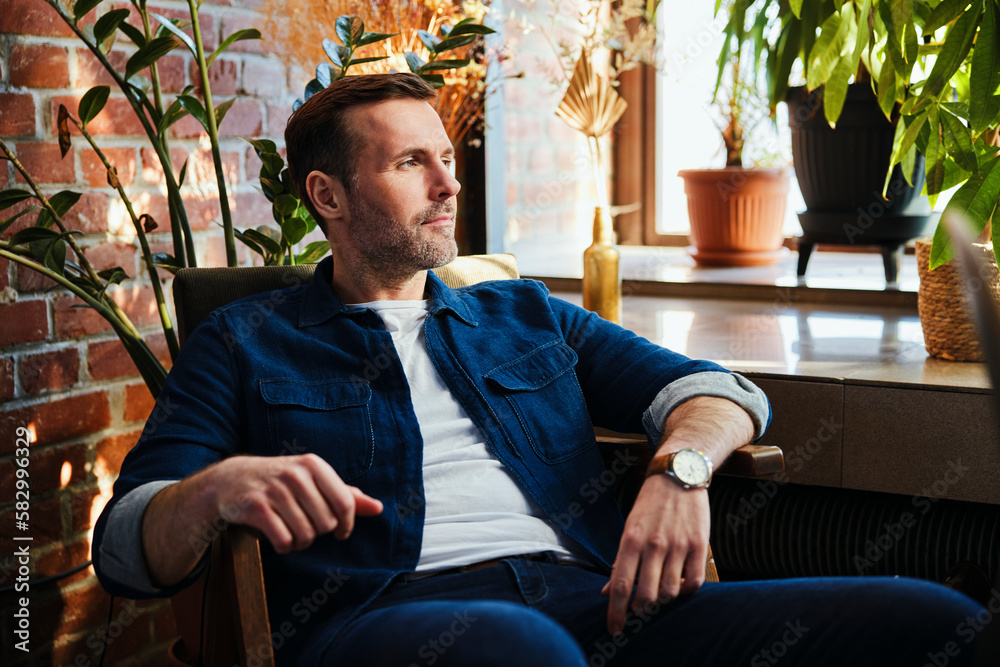 Thoughtful man sitting on chair in loft Stock Photo | Adobe Stock