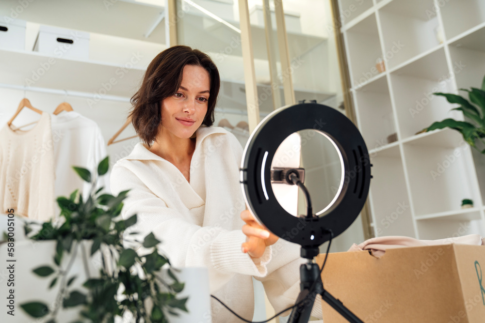 Young influencer using smart phone standing in front of ring light ...