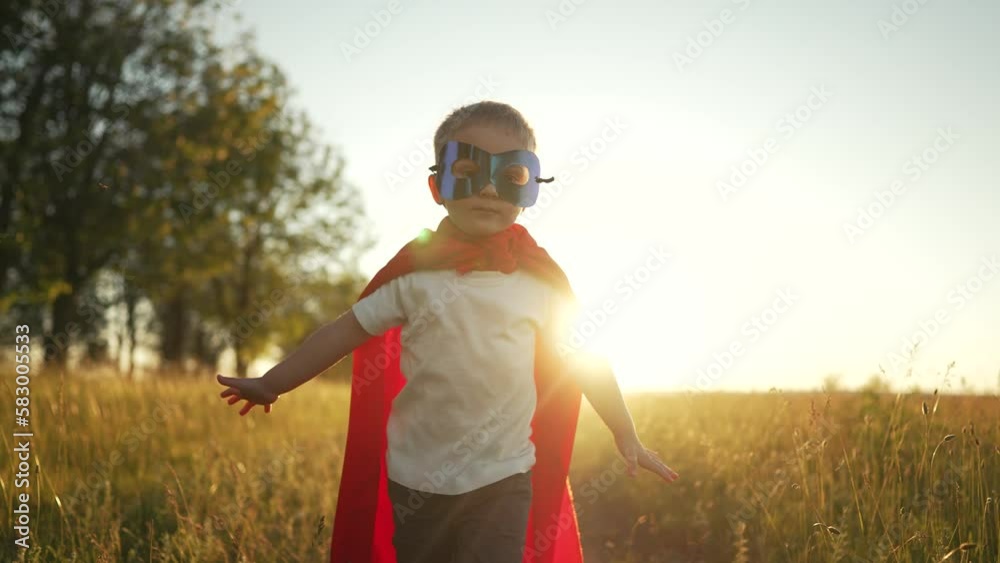 Stockvideon Happy child hero runs on green grass. Boy in a red ...