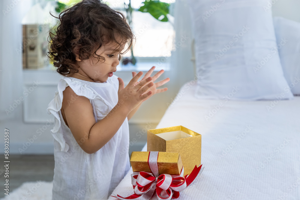 Cute young preschool Caucasian child girl with present box on sofa bed ...