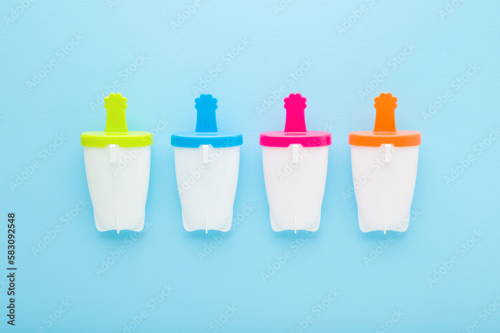 White plastic containers for homemade ice popsicle on colorful sticks ...