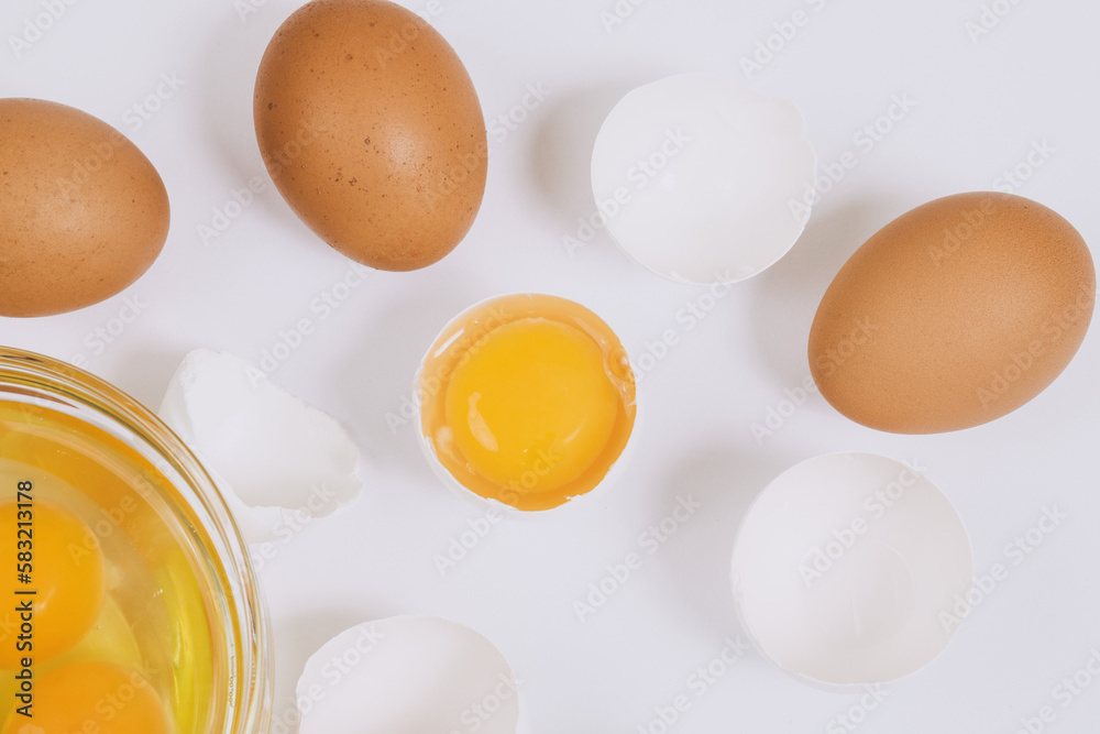 Whole brown eggs and cracked white eggs half with a yolk inside near ...