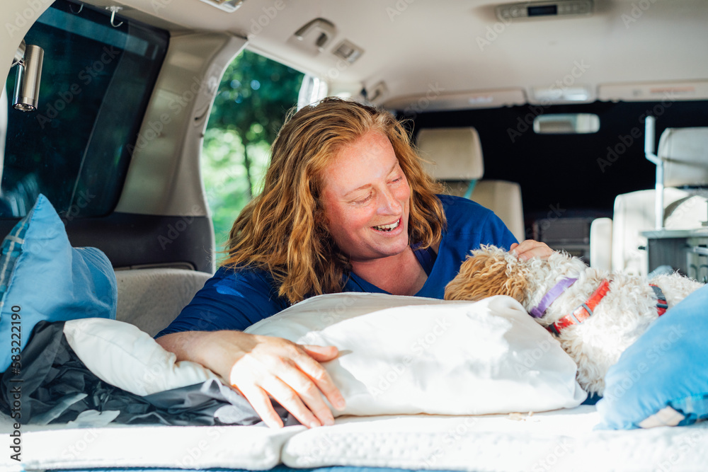 Laughing middle-aged woman having fun with cockapoo puppy pet while ...