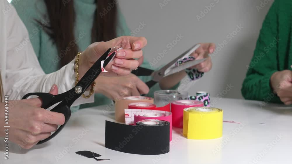 Lifting skin concept. Kinesiotaping. Girls sit at table and cut multi ...