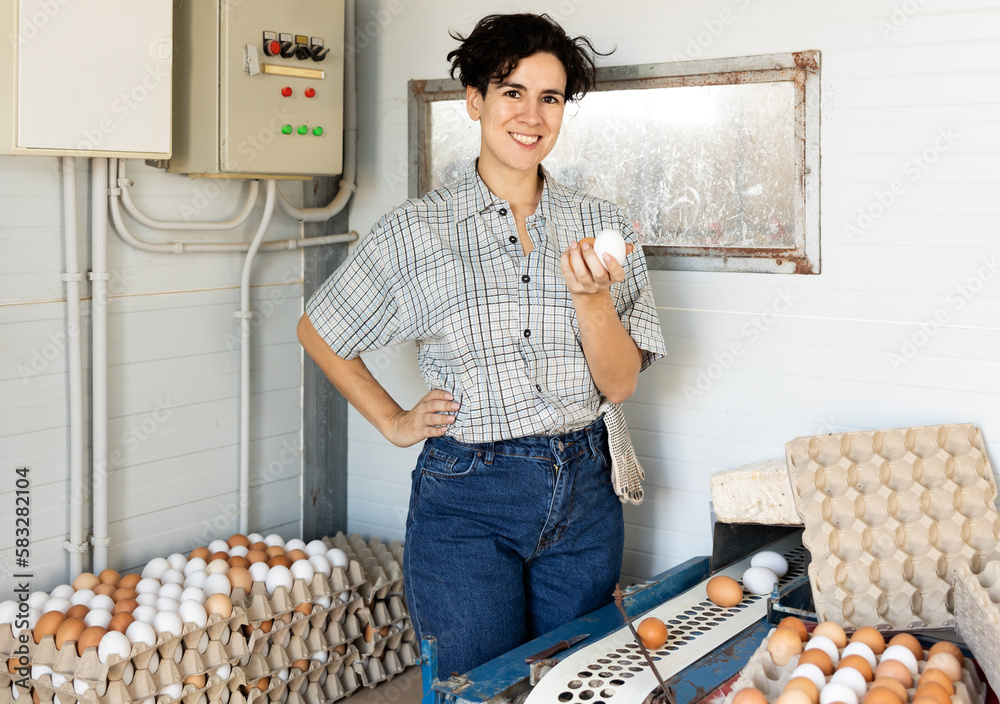 Smiling successful Hispanic female owner of poultry farm standing with ...